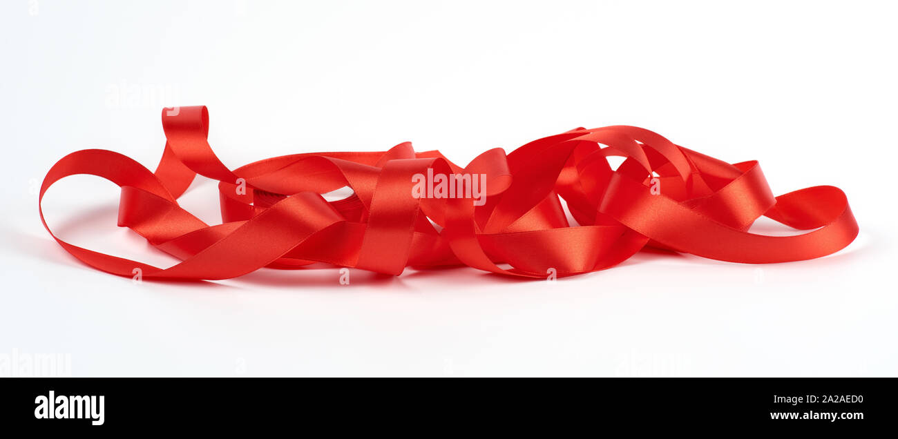 curled red satin ribbon on white background, festive backdrop, close up ...