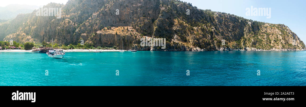panoramic of sailing ship moored in a bay with calm seas and mountains ...