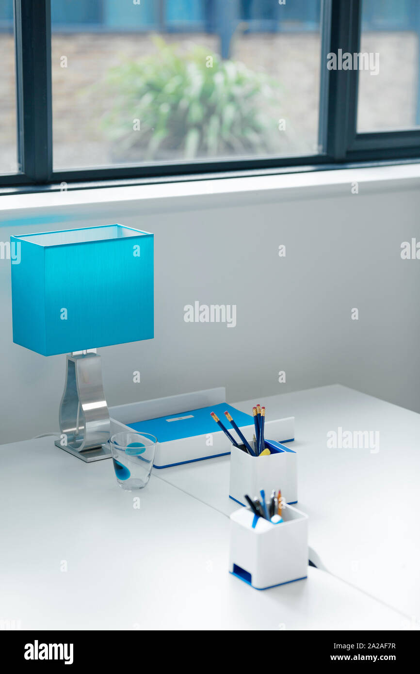 Modern blue office desk with lamp and files Stock Photo - Alamy