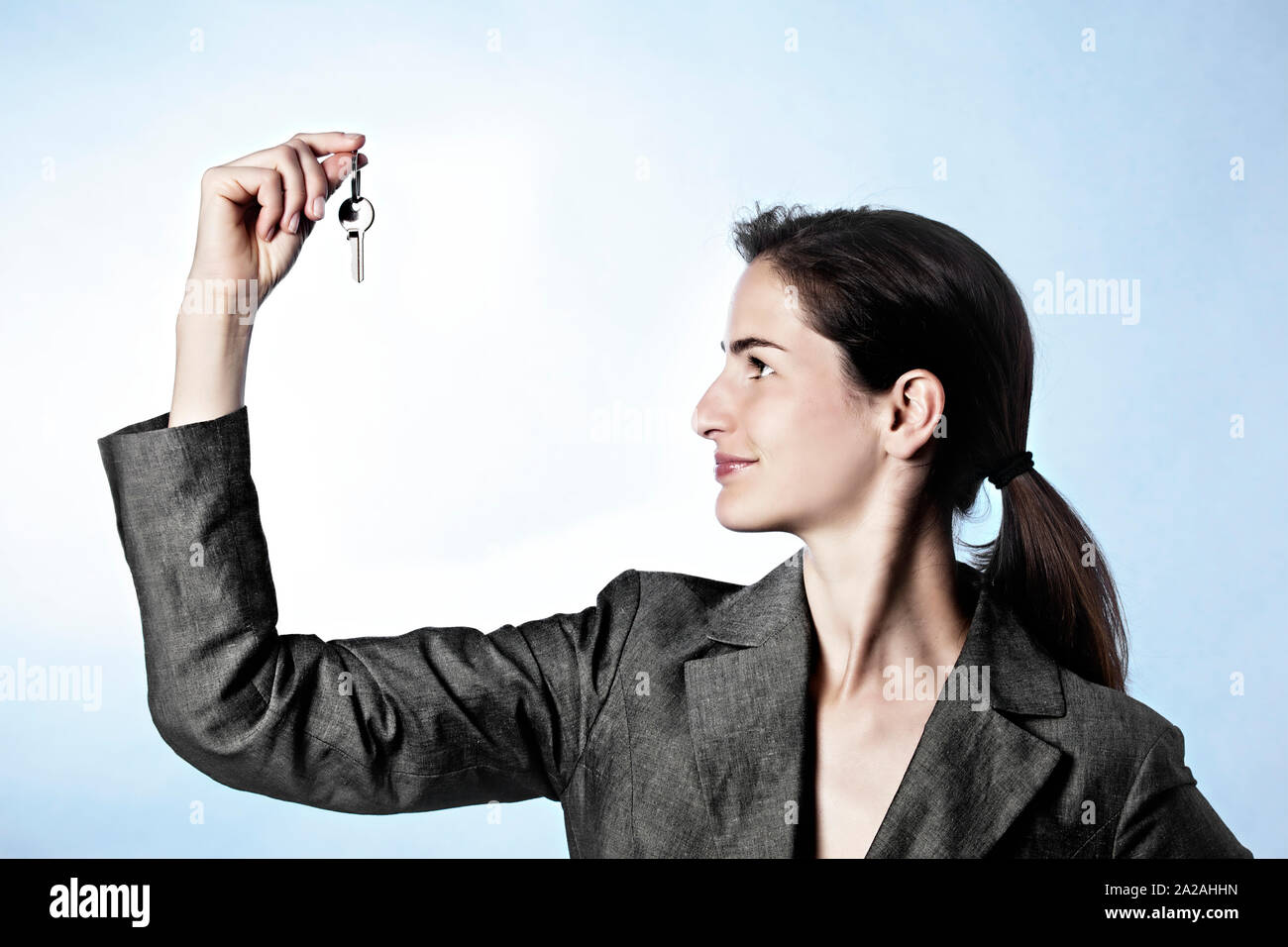 Profile of woman holding key between fingers Stock Photo - Alamy