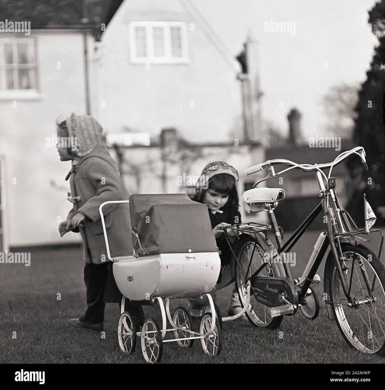 1960s, historical, two young girls outside in a large garden, one with ...