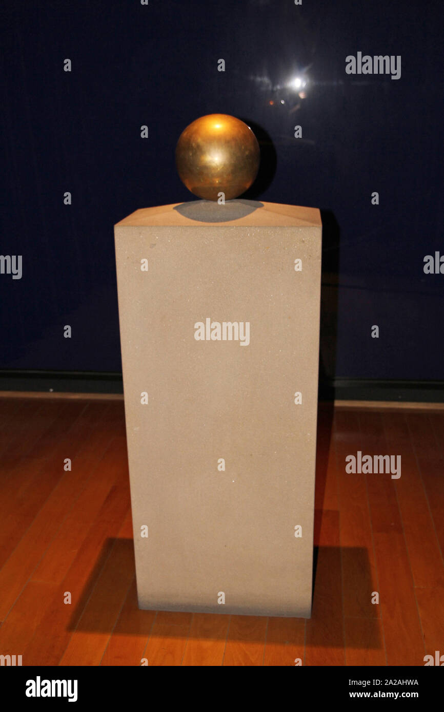 Golden sphere urn containing Nikola Tesla's ashes on display stand ...
