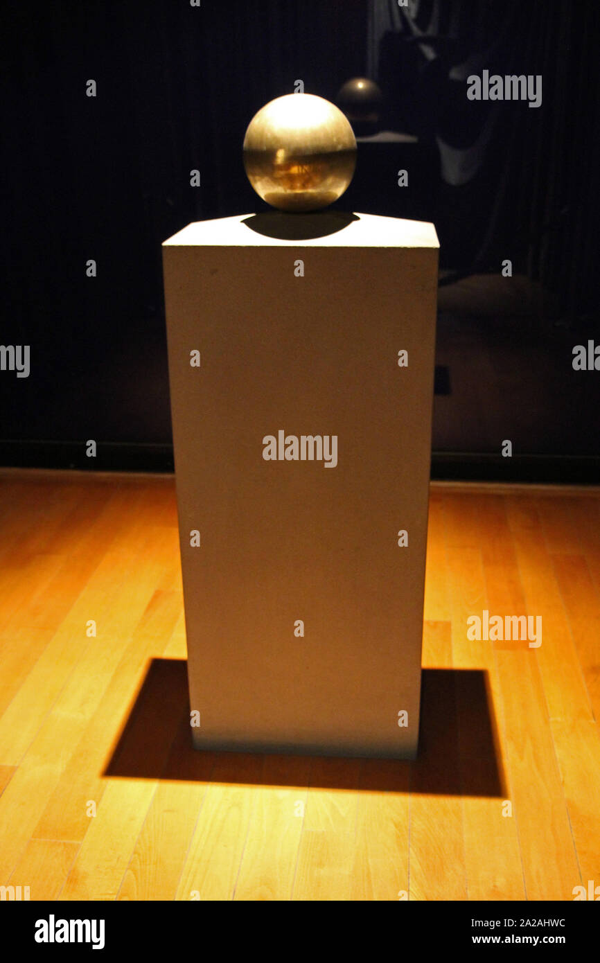 Golden sphere urn containing Nikola Tesla's ashes on display stand ...