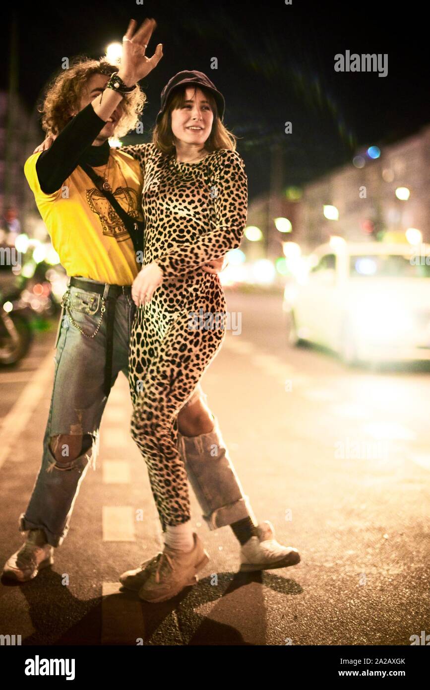 man and woman entangled, standing at street at night, nightlife in ...