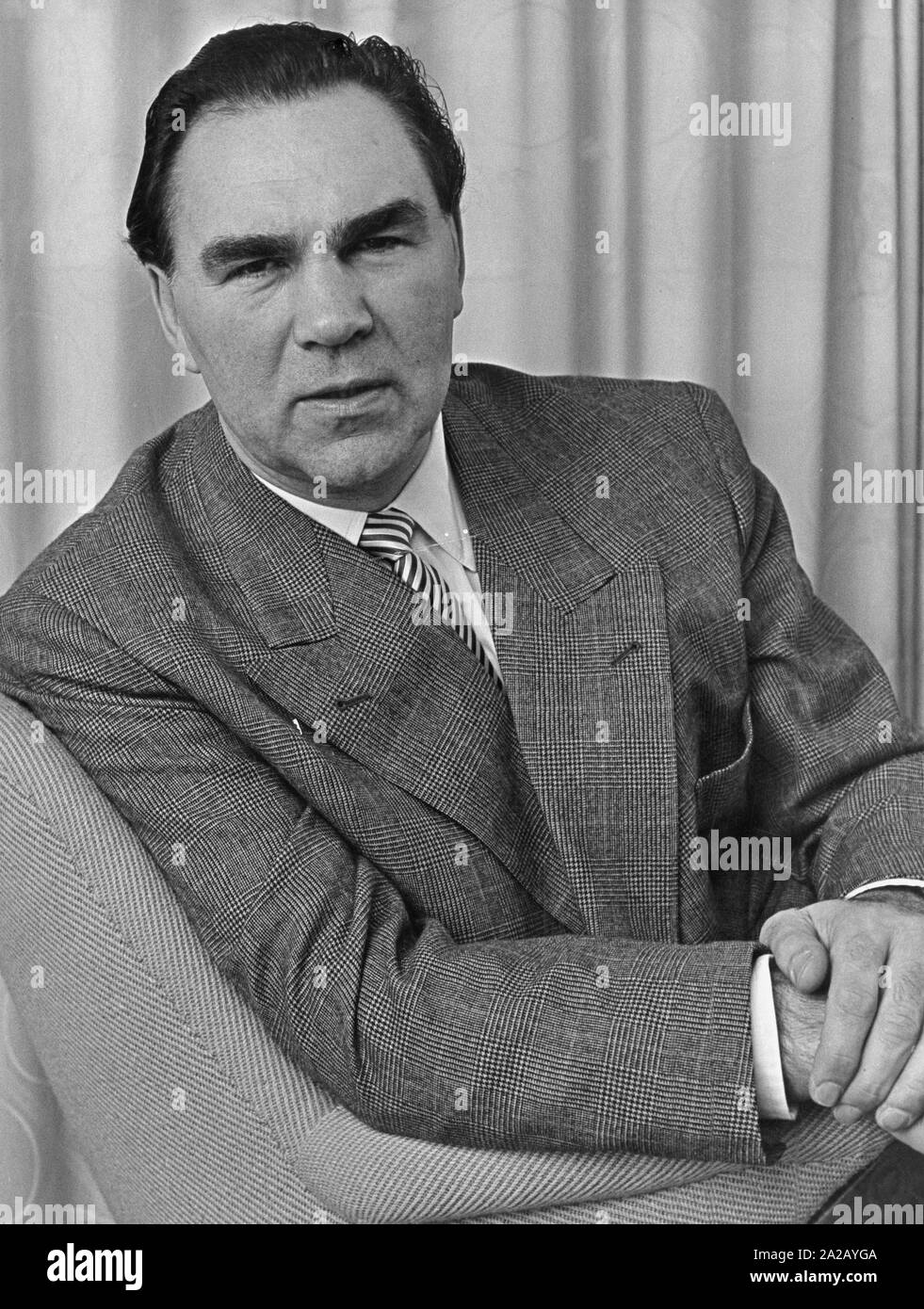 Max Schmeling posing in a chair in shirt with tie and plaid jacket ...