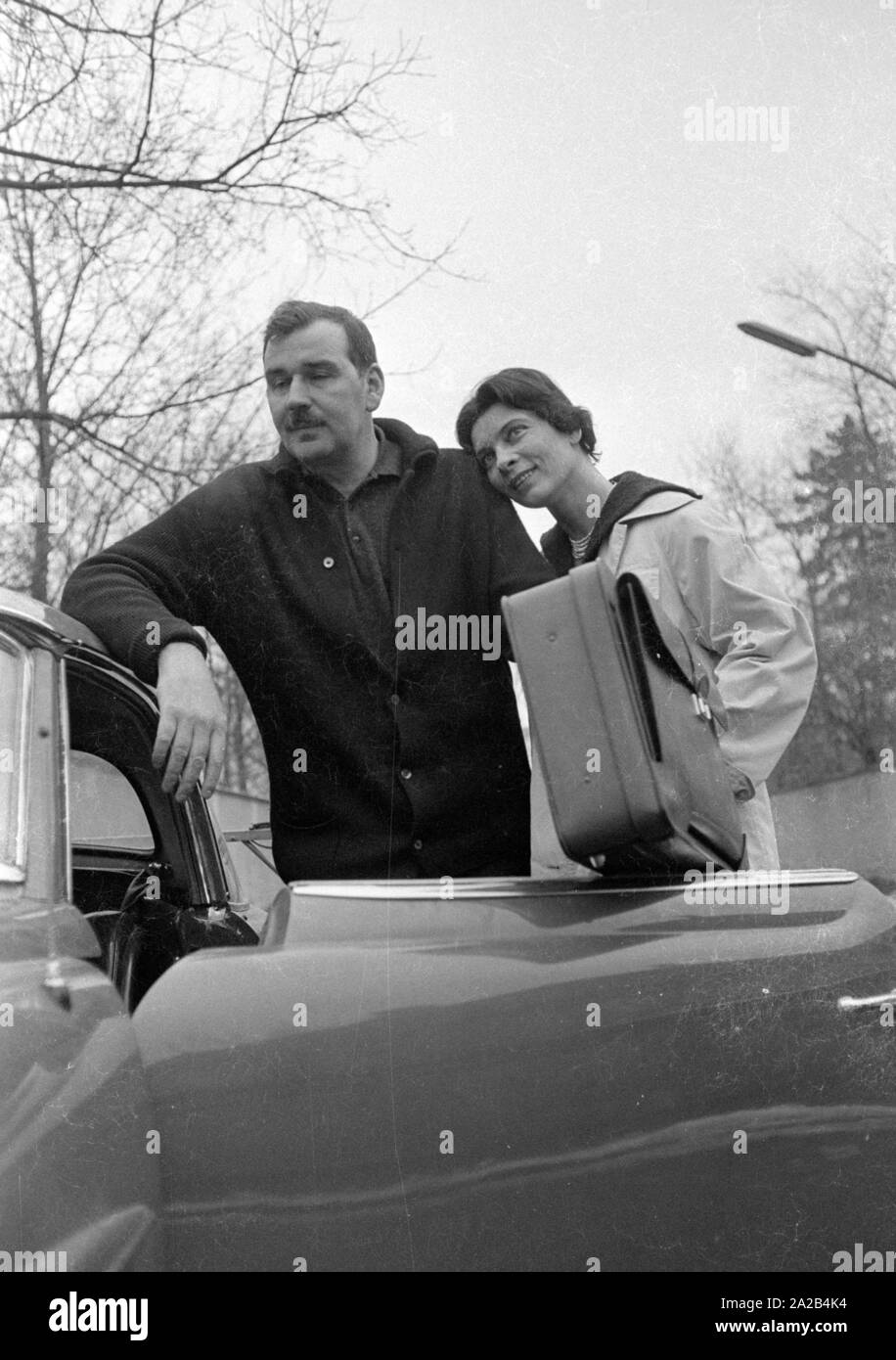 Bernhard Wicki stands at the driver's door of his sports car together ...