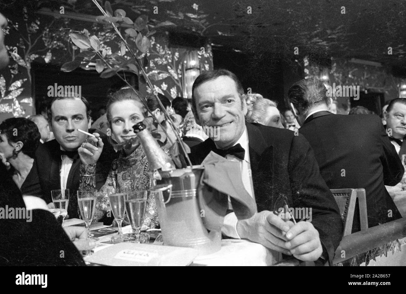 Hellmut Lange sitting at a table filled with glasses and champagne with ...