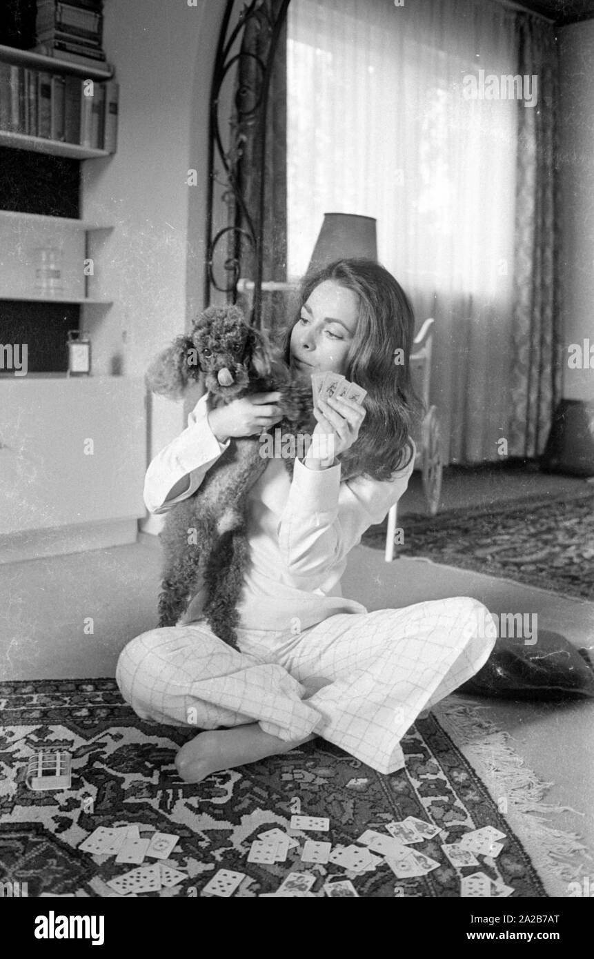 German actress Karin Dor sits on the carpet and plays with cards and ...
