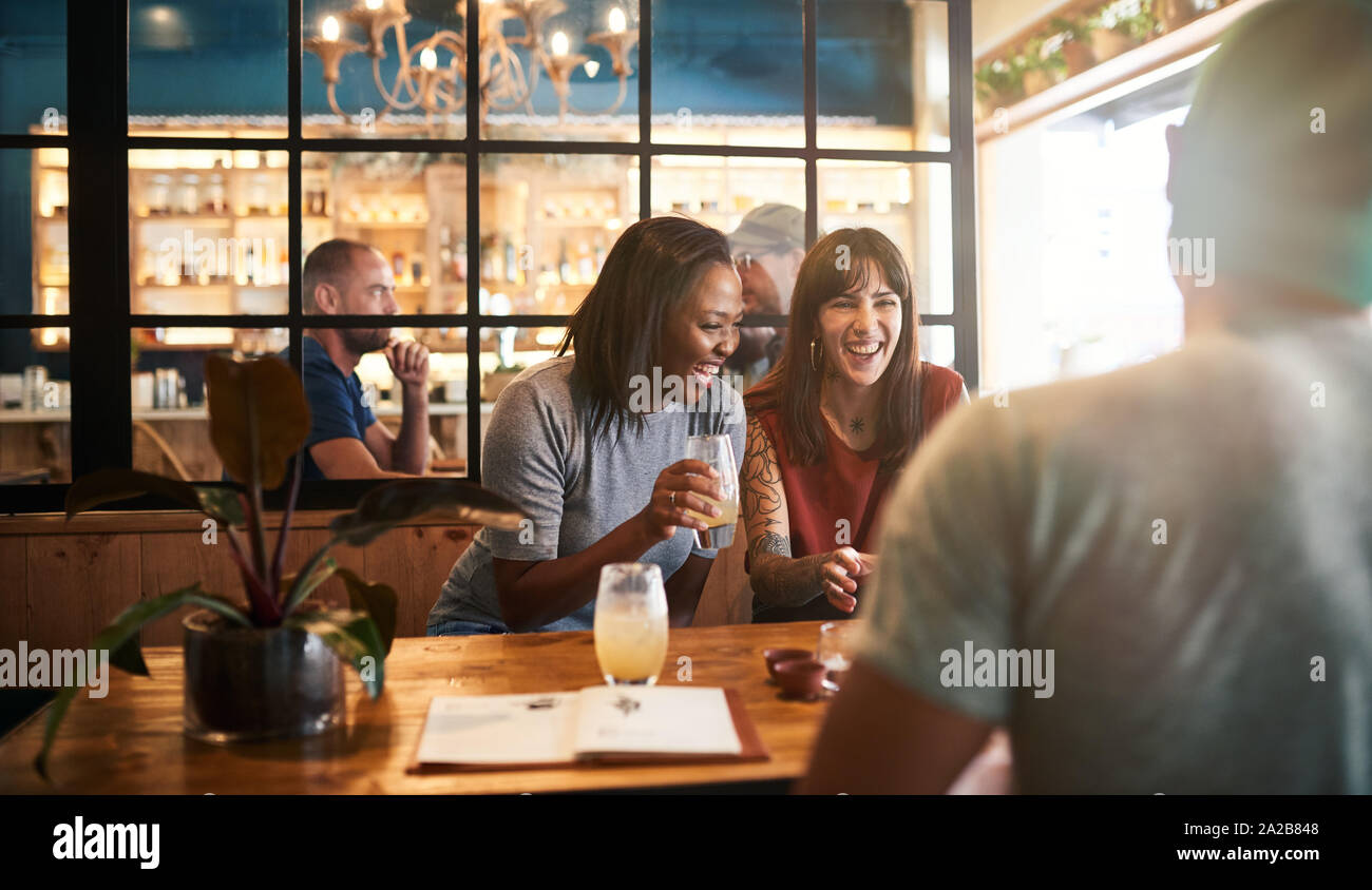 Diverse young friends laughing over drinks together in a bar Stock ...