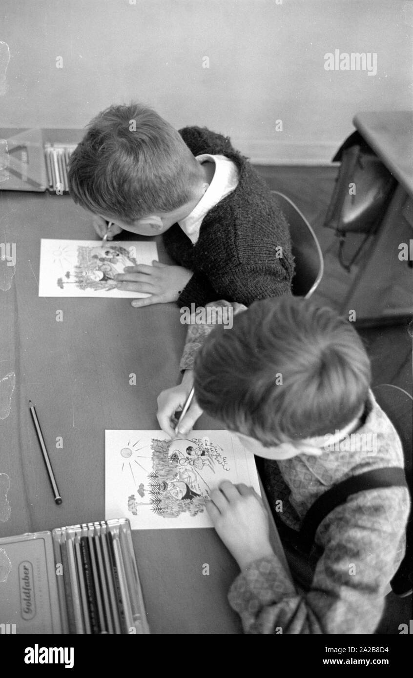 Two elementary students color drawingswith crayons. The drawing shows ...