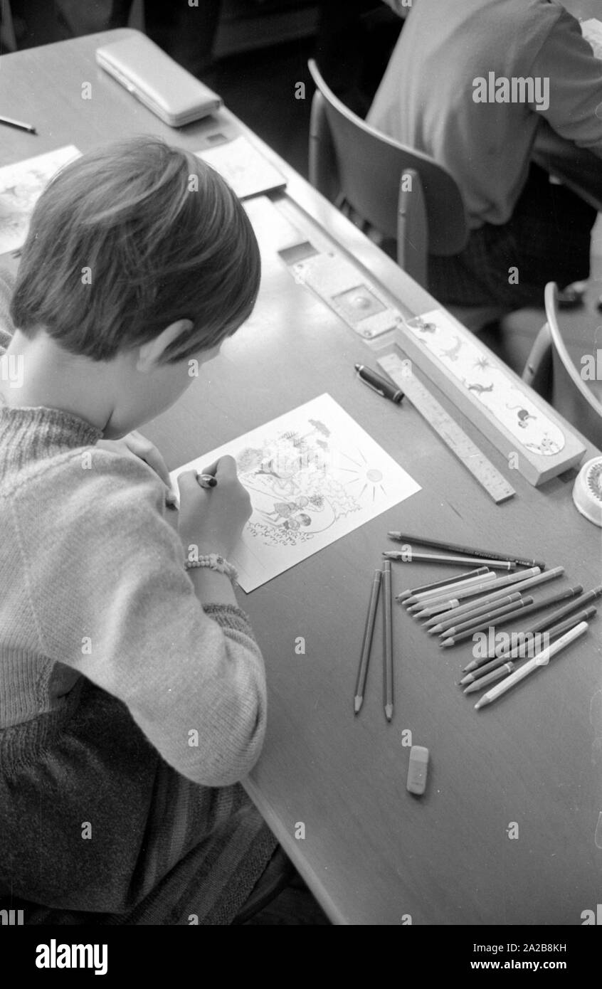 Primary students color pictures with crayons. The drawing shows ...