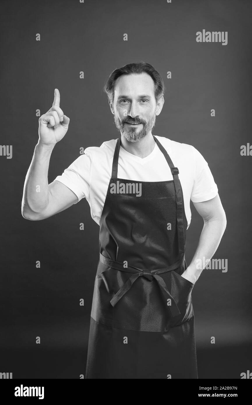 Culinary magic. Cook with beard and mustache wearing apron red ...