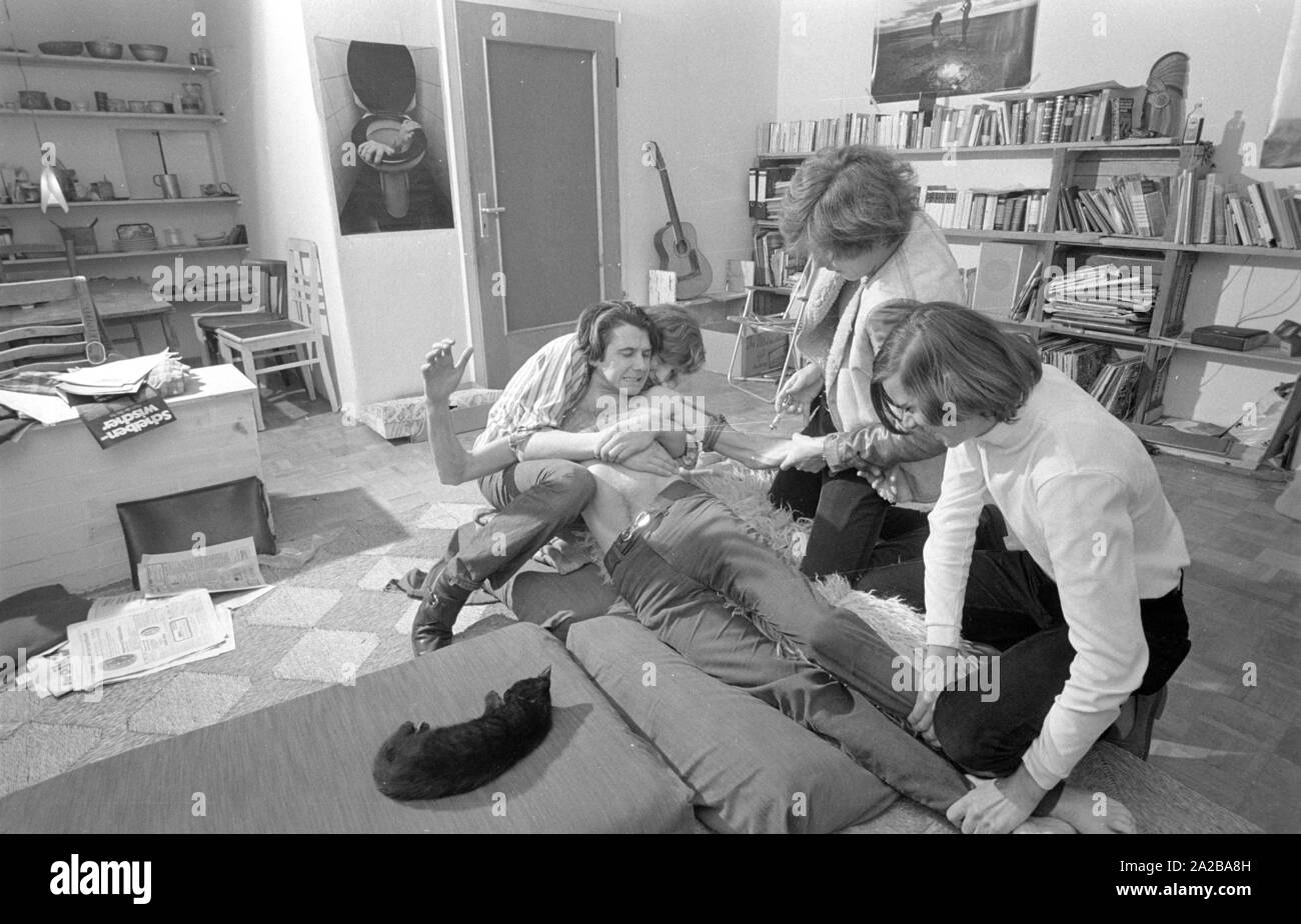 Young people using drugs with a syringe. One of the adolescents is ...