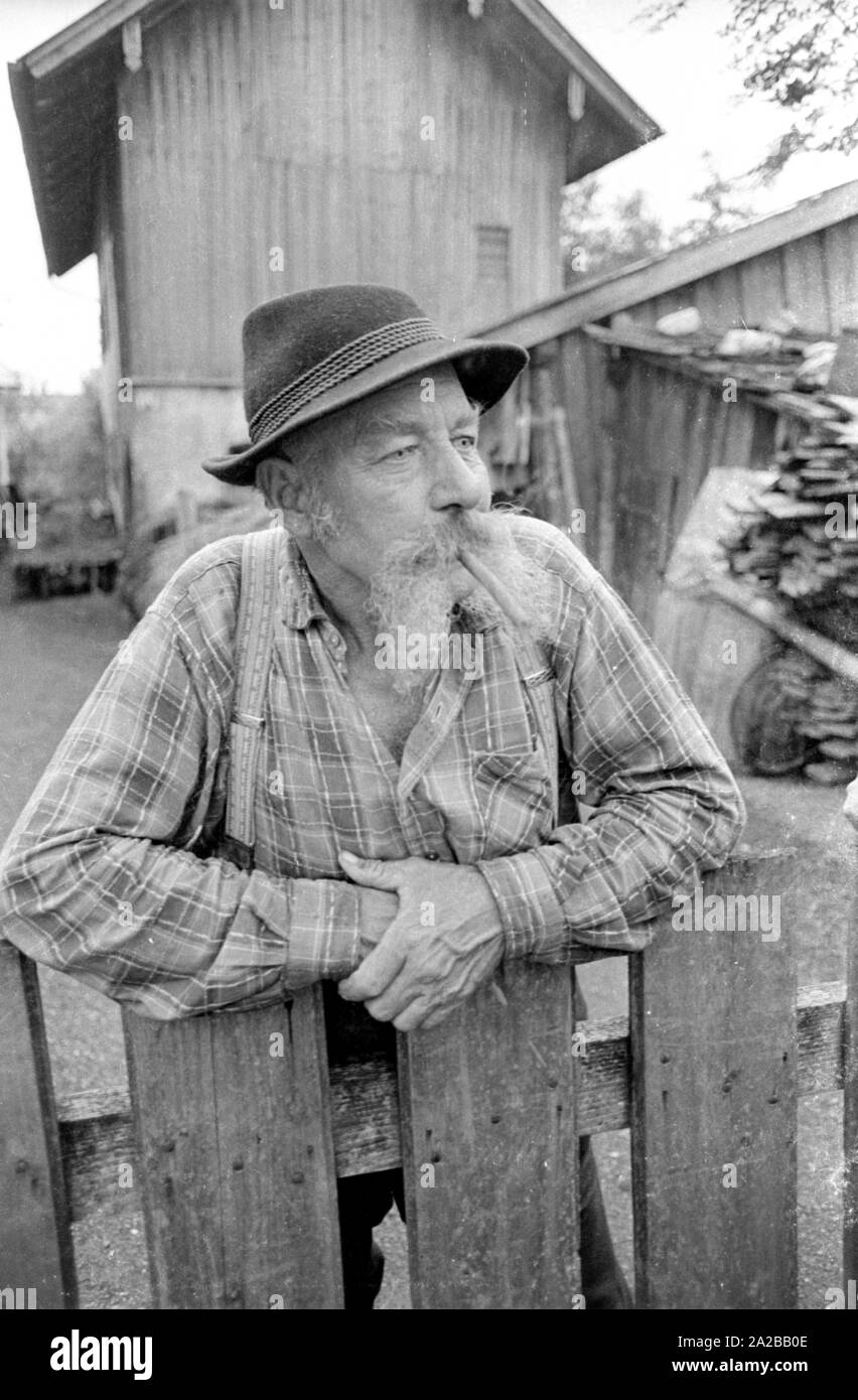 An old man is leaning against the garden fence and smokes Stock Photo ...