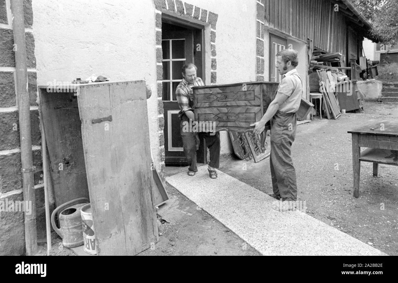 The employees of a joiner's workshop carry a new dresser out of the ...