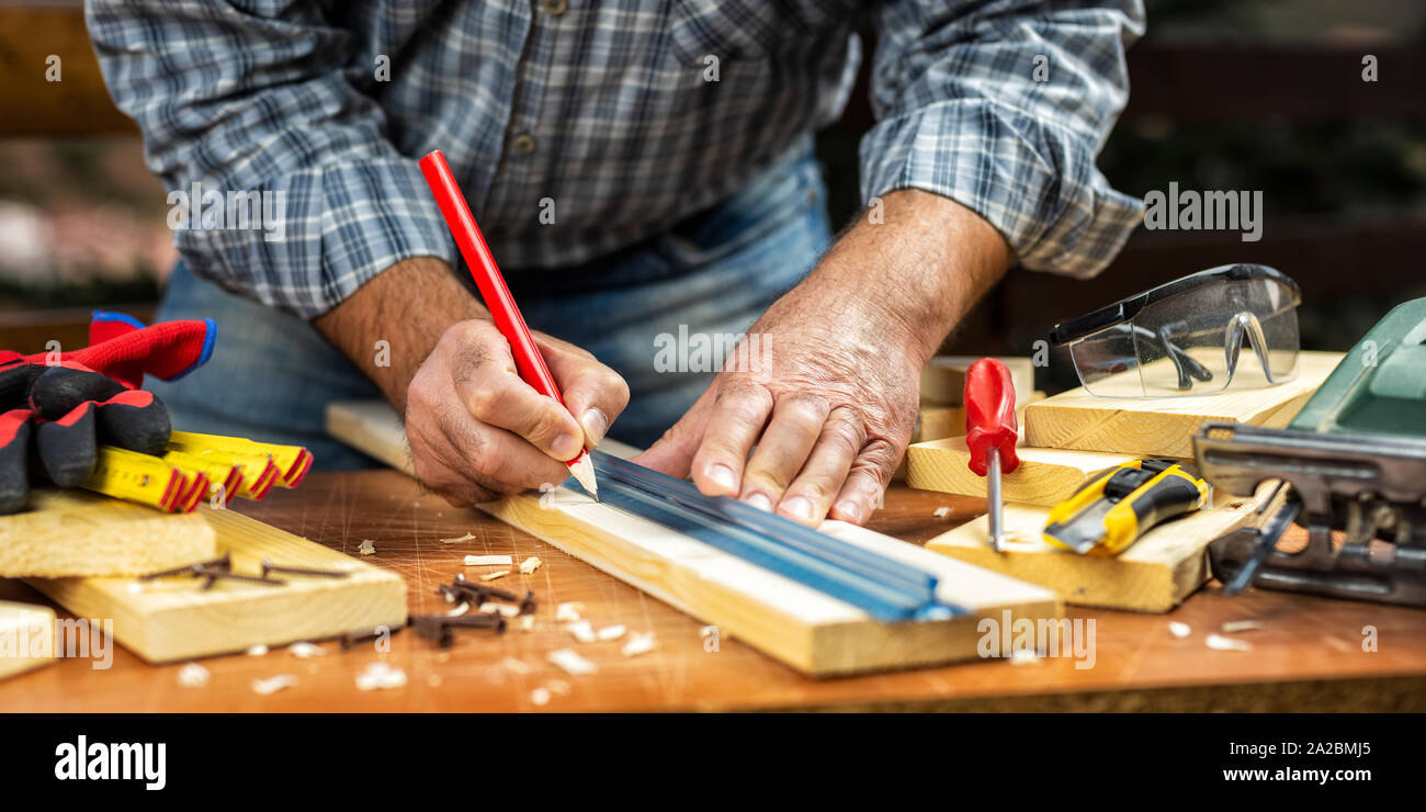 Adult craftsman carpenter with pencil and ruler tracing the cutting ...