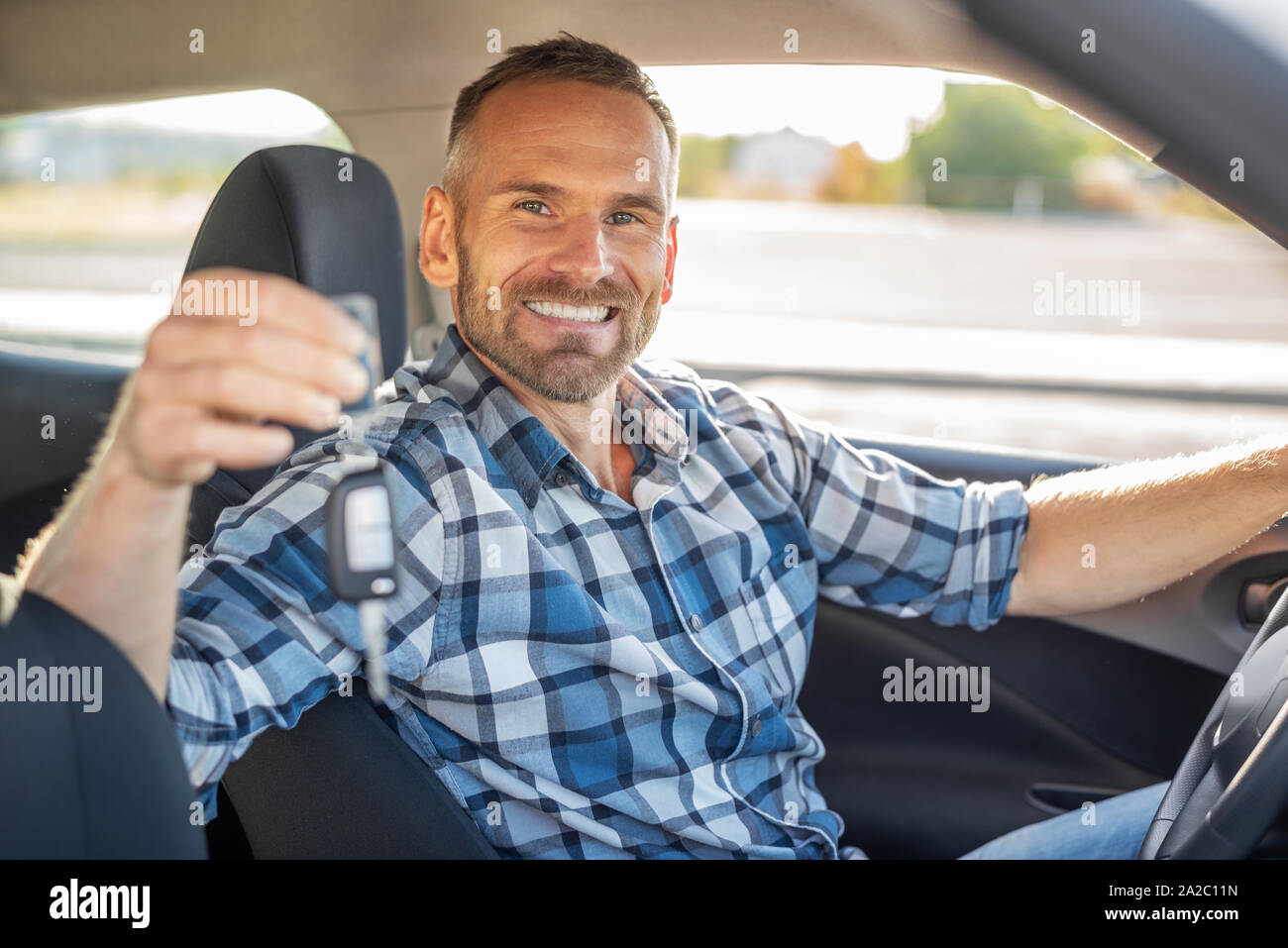 A man in a car shows a key Stock Photo - Alamy