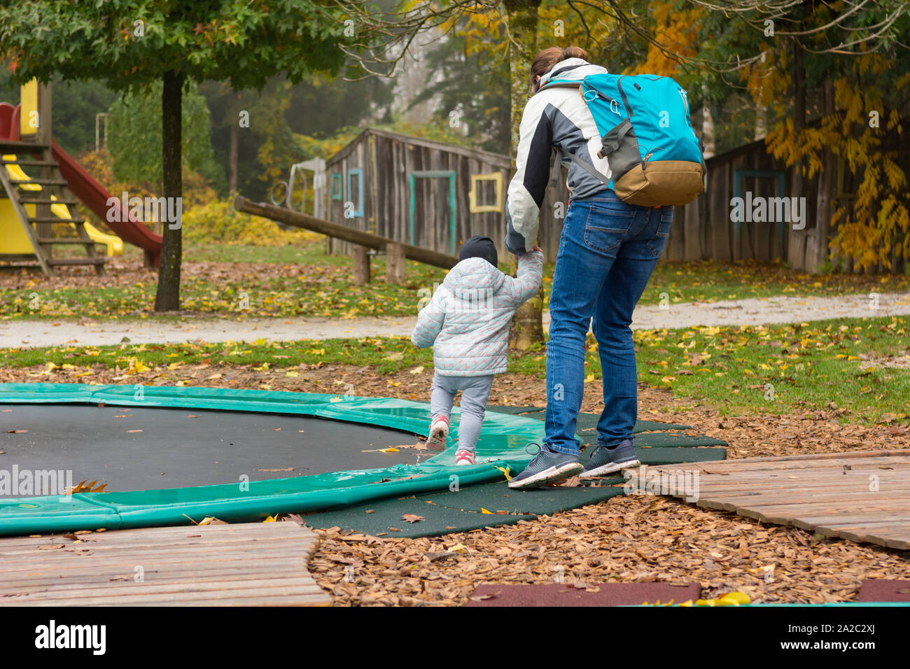 Mother and daughter walking through children playground with ...