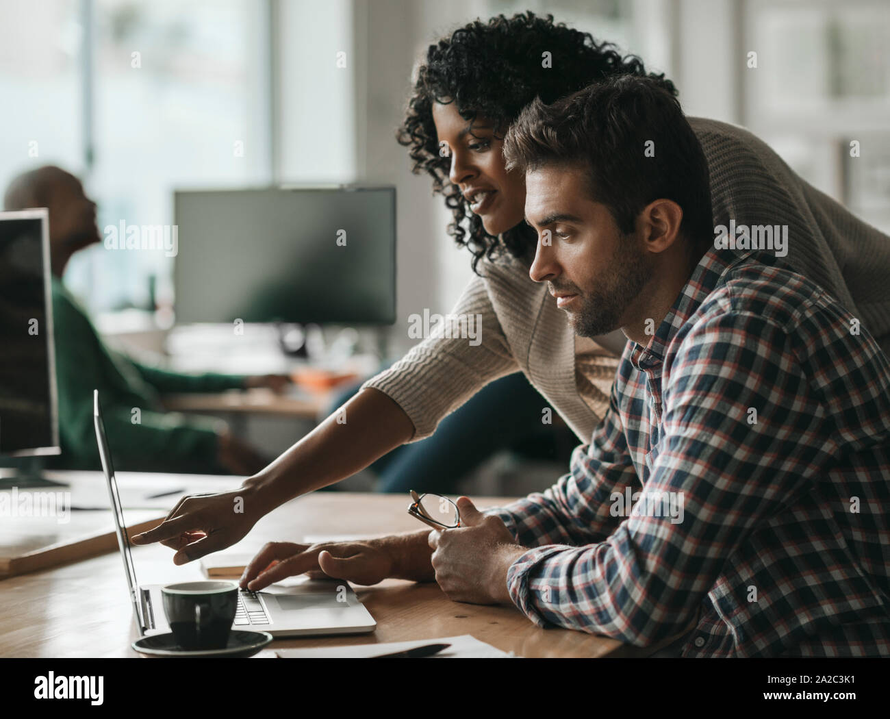Two designers working on a computer together in an office Stock Photo ...