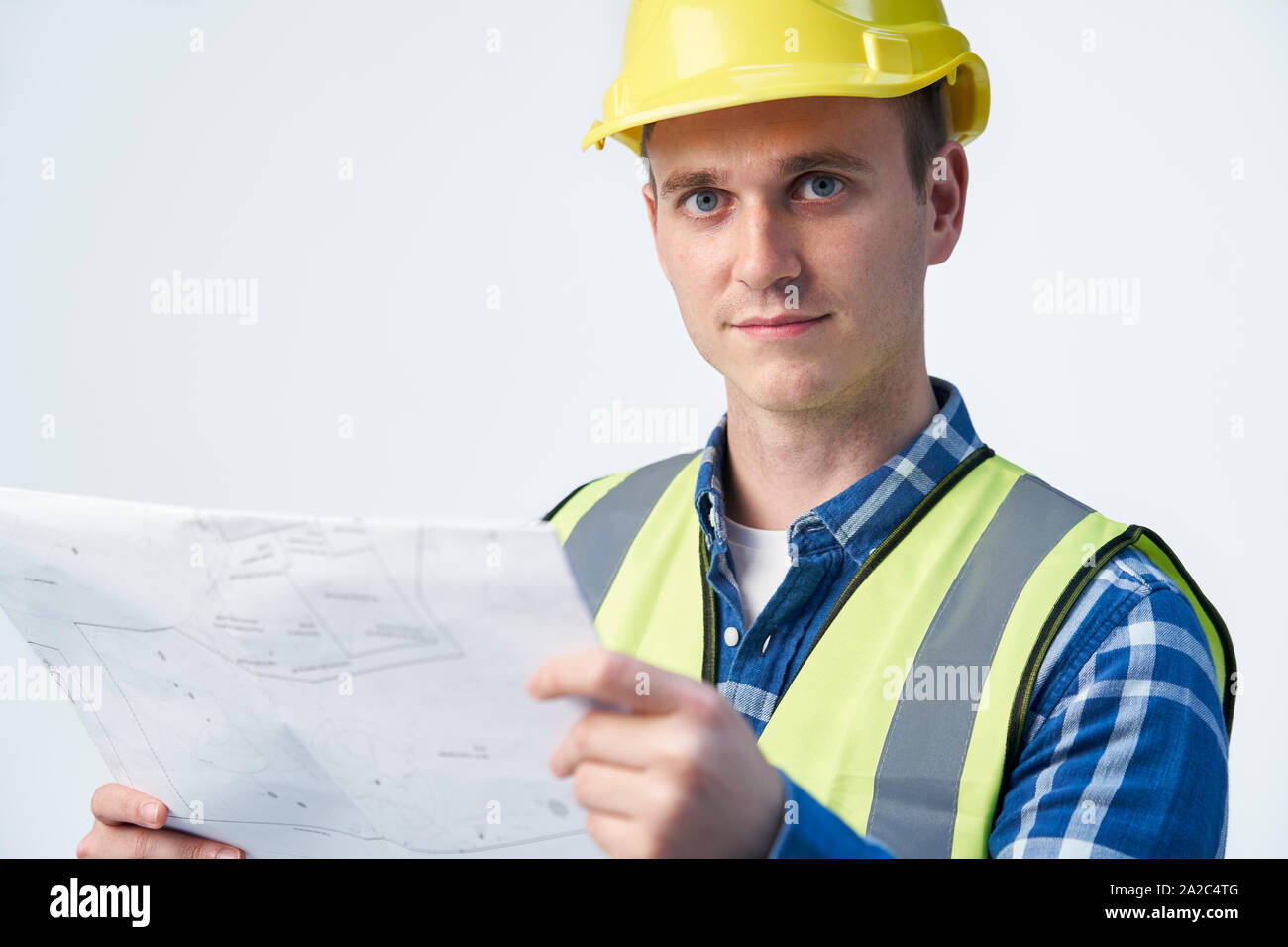Studio Portrait Of Builder Architect Looking At Plans Against White ...