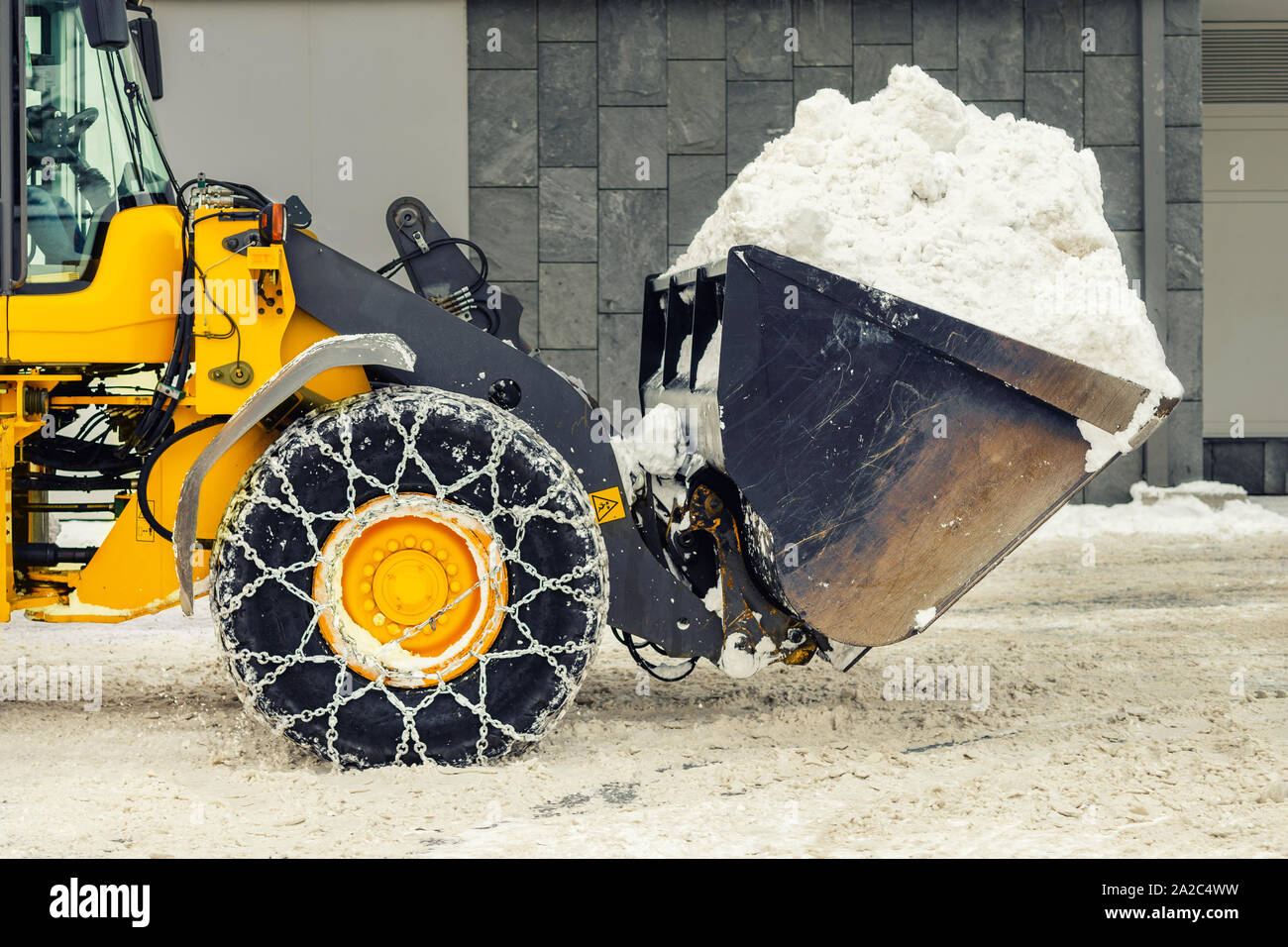 Big loader machine with steel metal chains removing big snow pile from ...