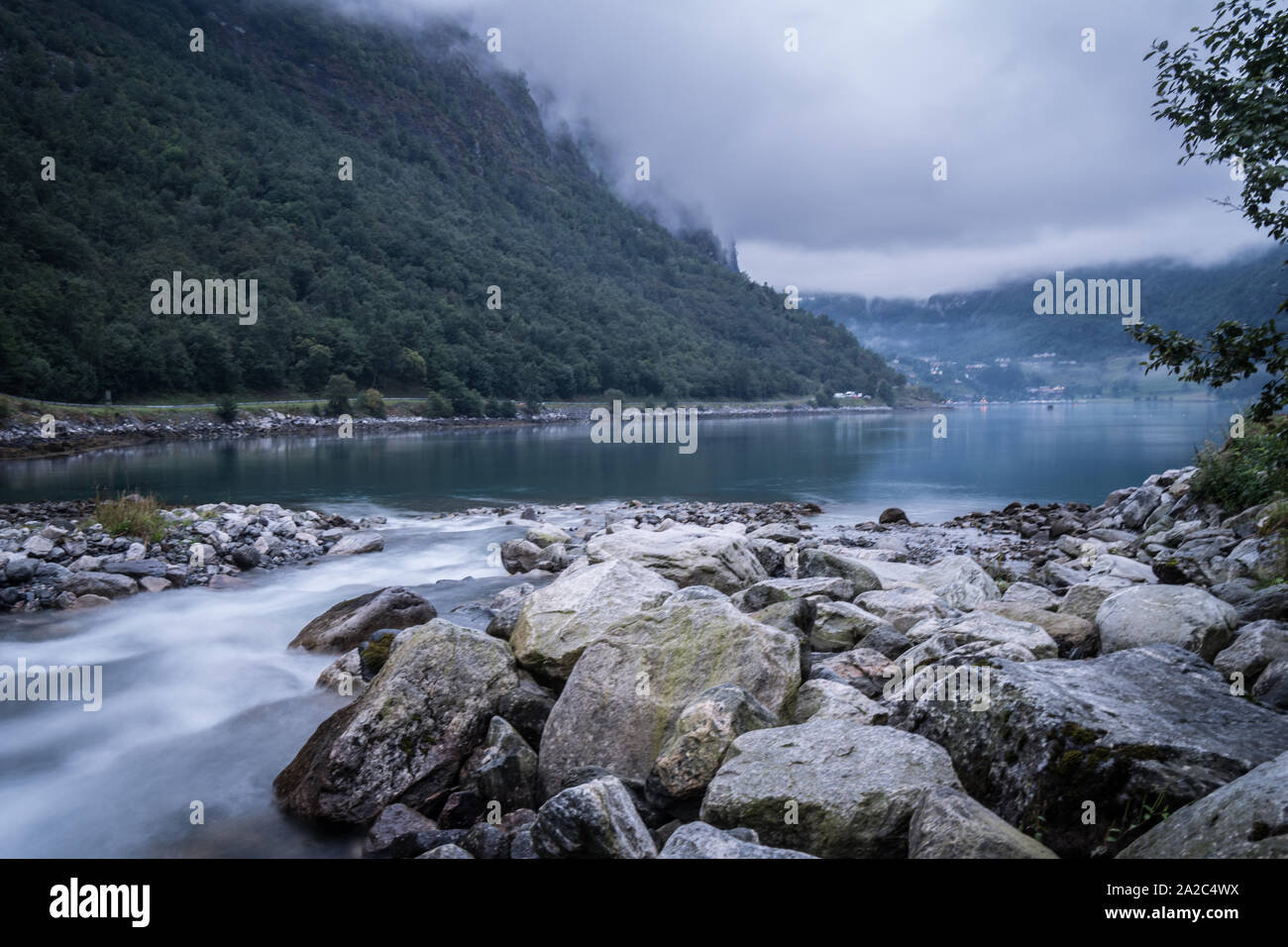 Late evening view of smooth river water and rocks of shore Stock Photo ...