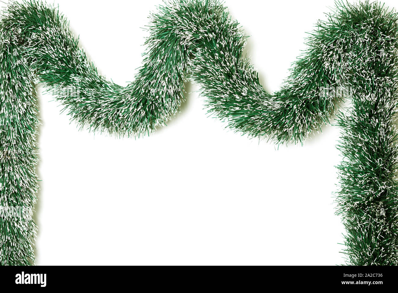 Green Christmas tinsel hanging with snow tipped ends isolated on white ...