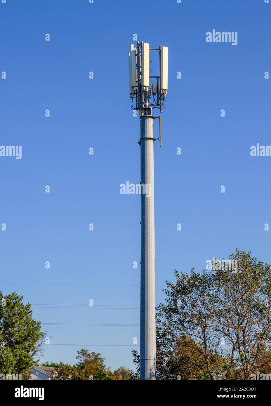 Mobile phone and communications mast photographed against a bright blue ...