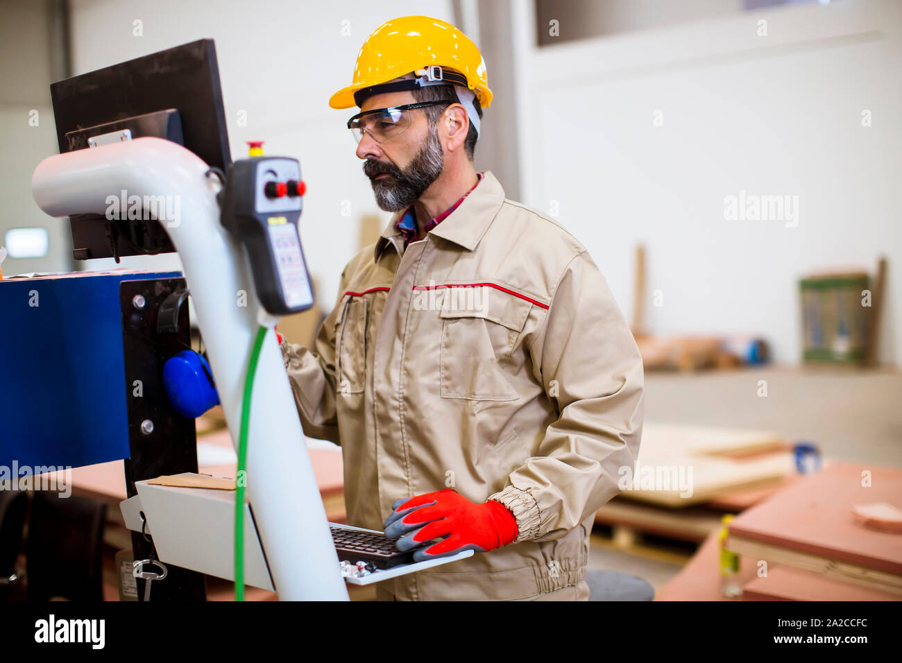 Portrait of senior man operating machine units in modern wooden factory ...