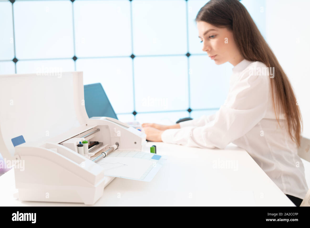 Young woman in the office of the printing company sets up a plotter for ...