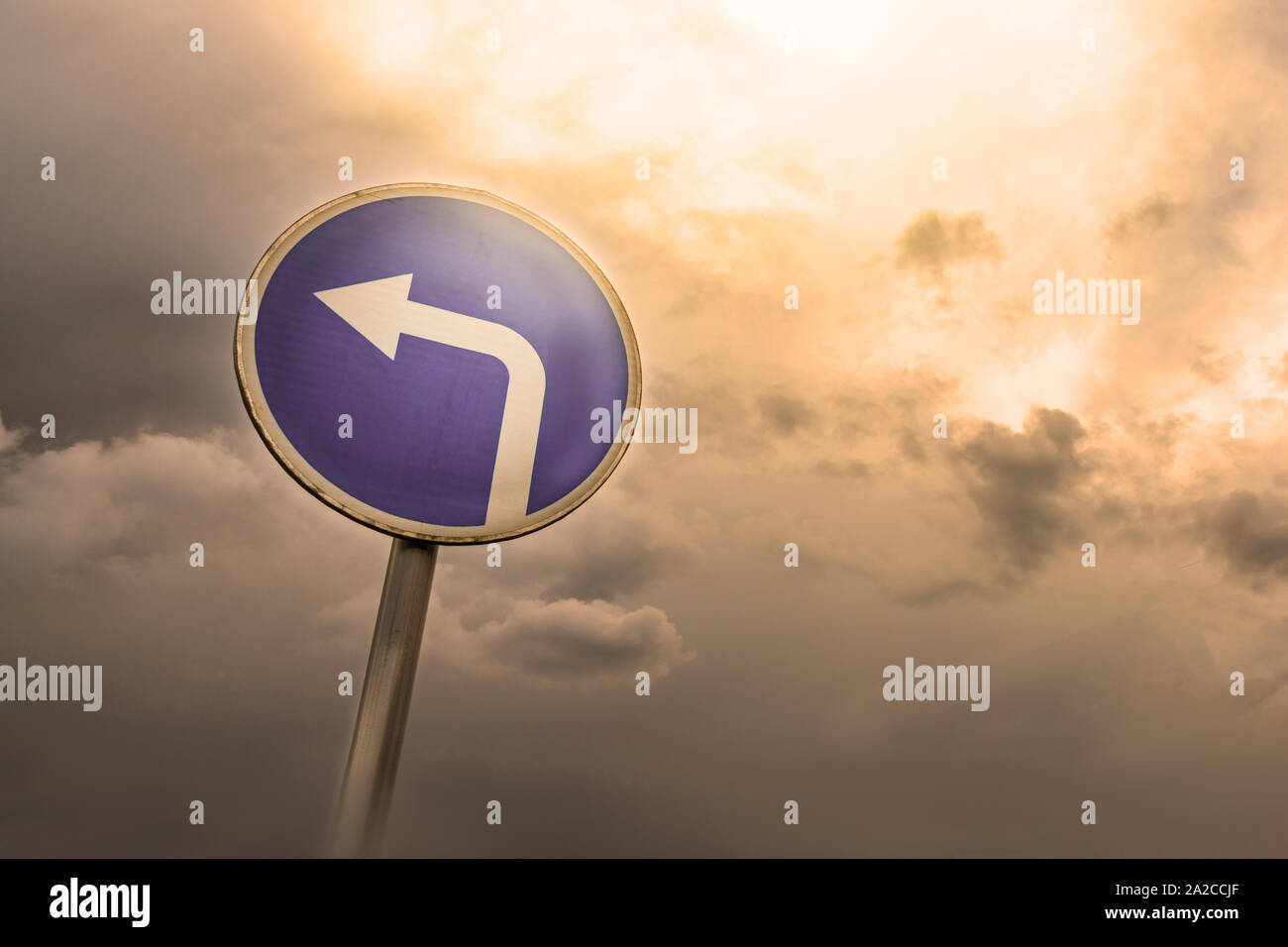 Turn left ahead sign, blue round roadside traffic signage, against the ...