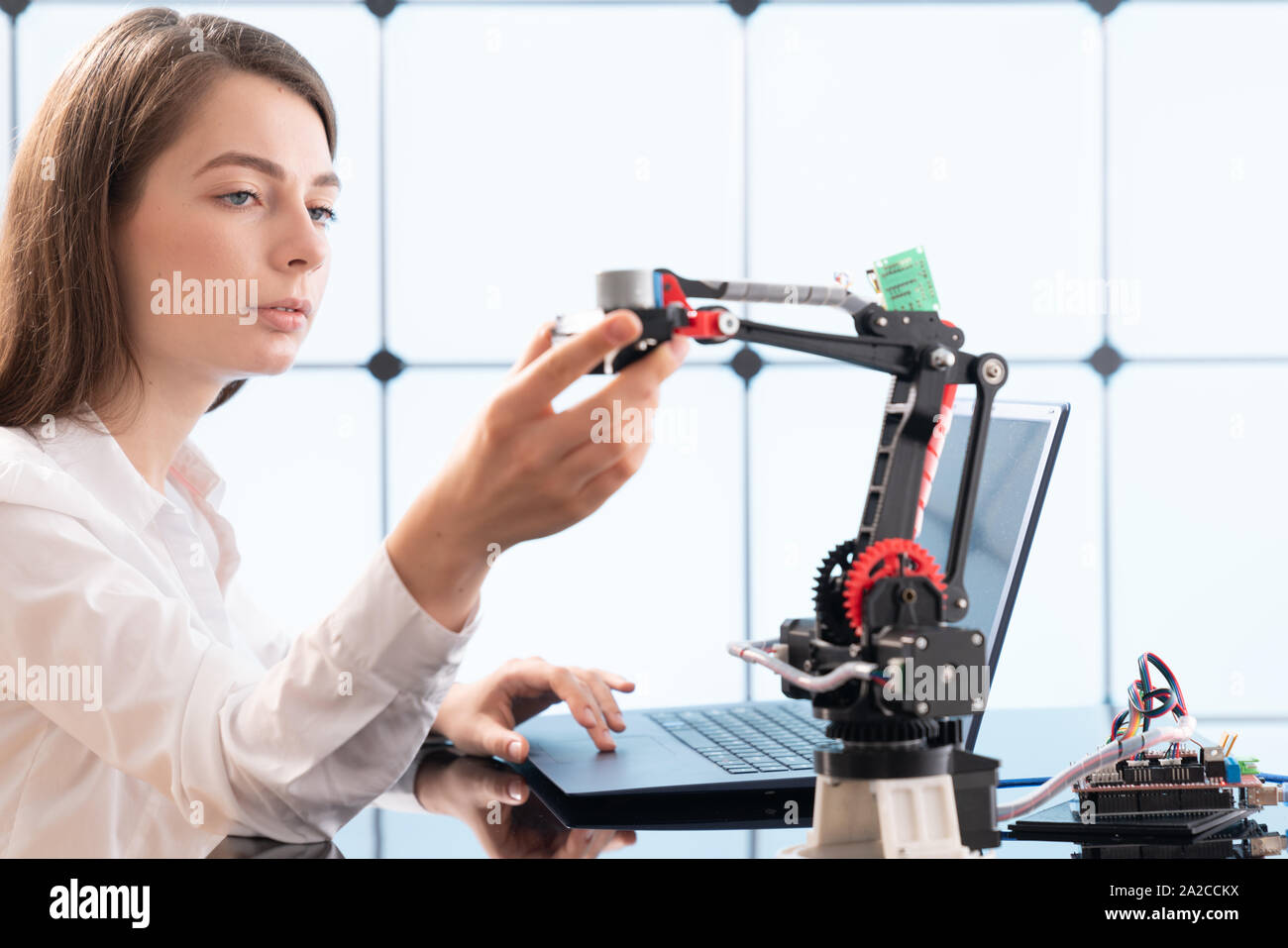 A young woman writes an algorithm for the robot arm. Science Research ...
