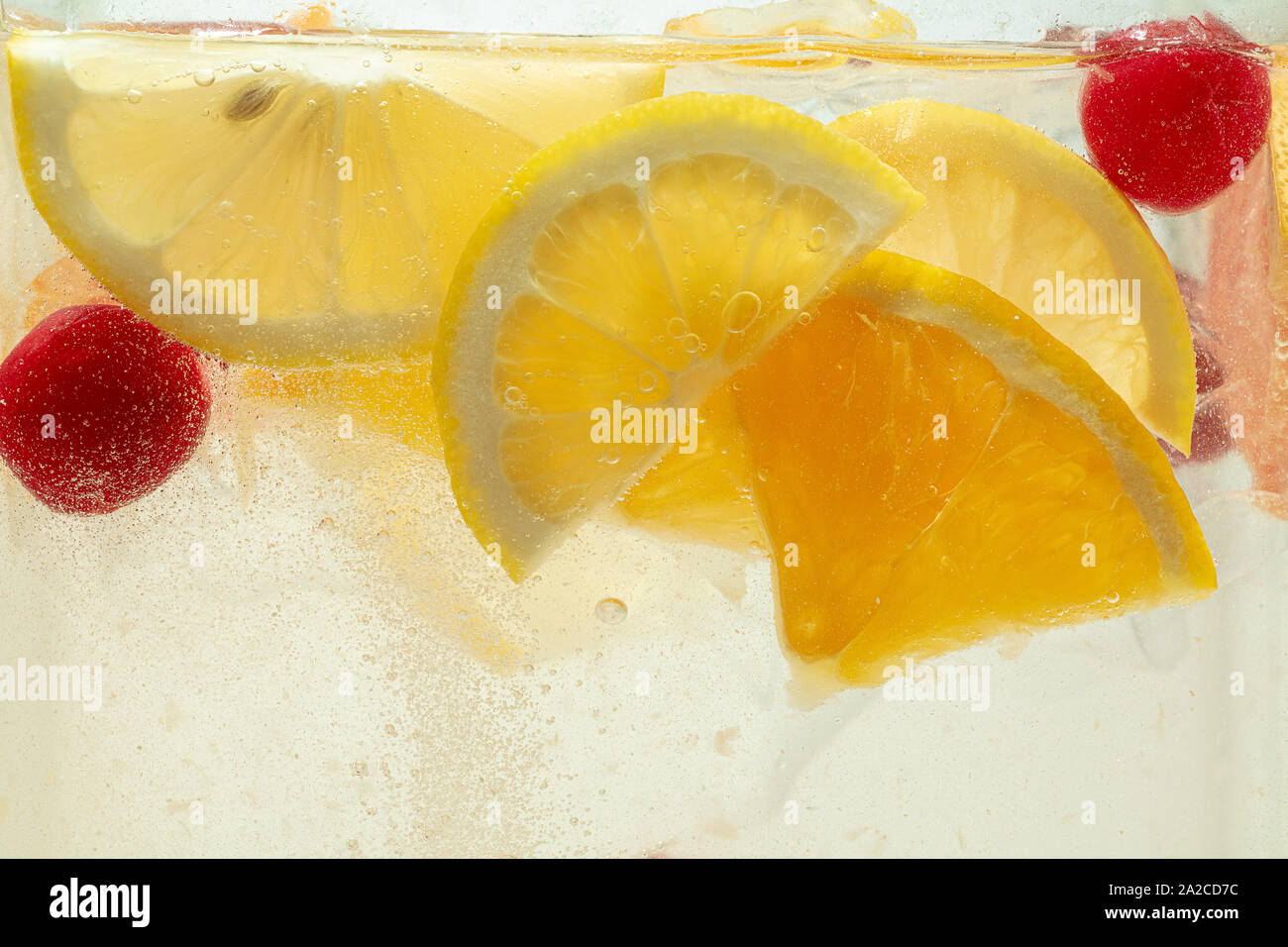 Close up of lemon slices and cherry in lemonade and ice cubes ...