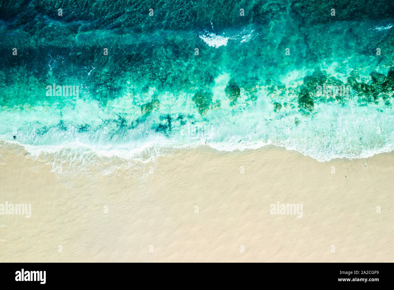 Aerial view looking down onto a tranquil cove with large waves breaking ...