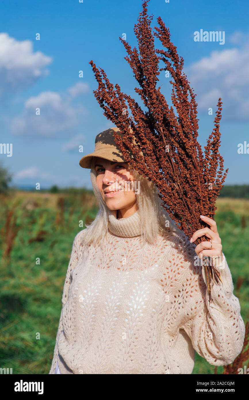 Happy beautiful blond woman dressed in a cap, sweater and white long ...