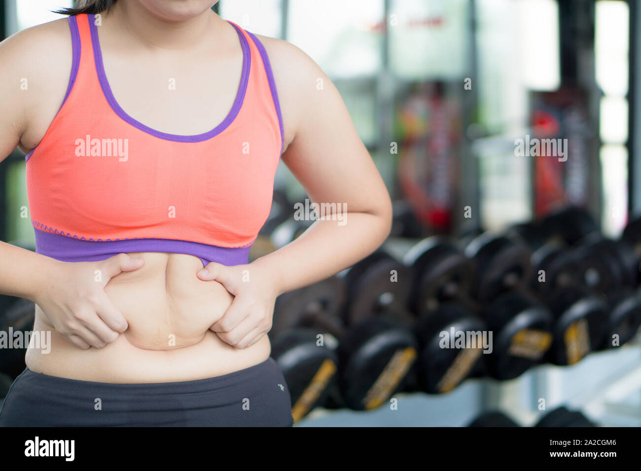 Close up woman holding excessive fat belly at fitness gym. Diet, weight ...
