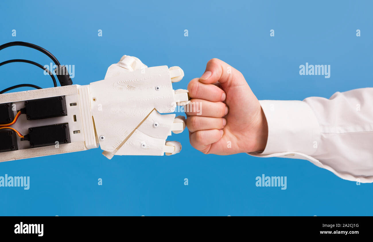 Robot and human hand making fist bump gesture Stock Photo - Alamy