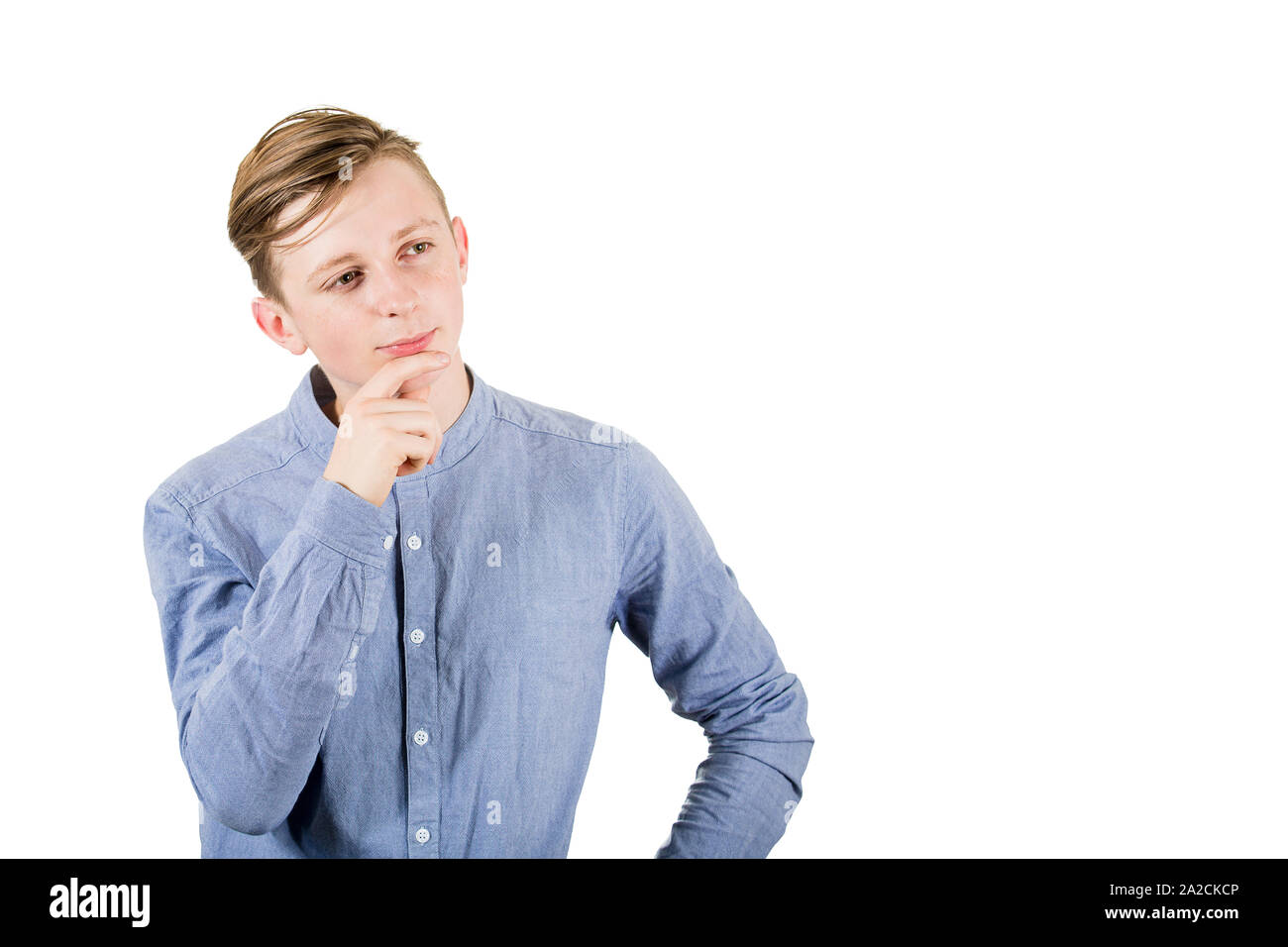 Smart teenage boy thinking, keeps hand under chin looking aside ...