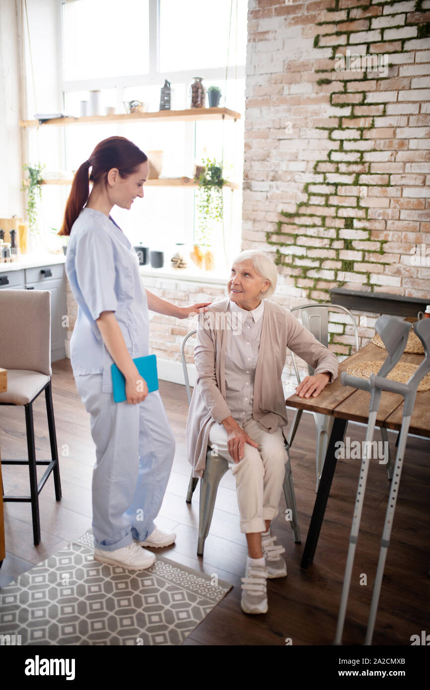 Helpful nurse wearing uniform talking to patient Stock Photo - Alamy