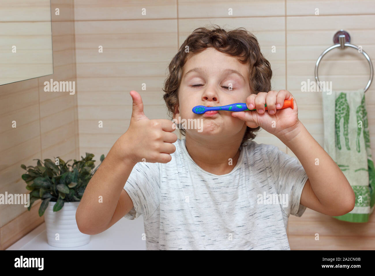 Cute little boy is brushing his teeth with toothbrush and showing thumb ...