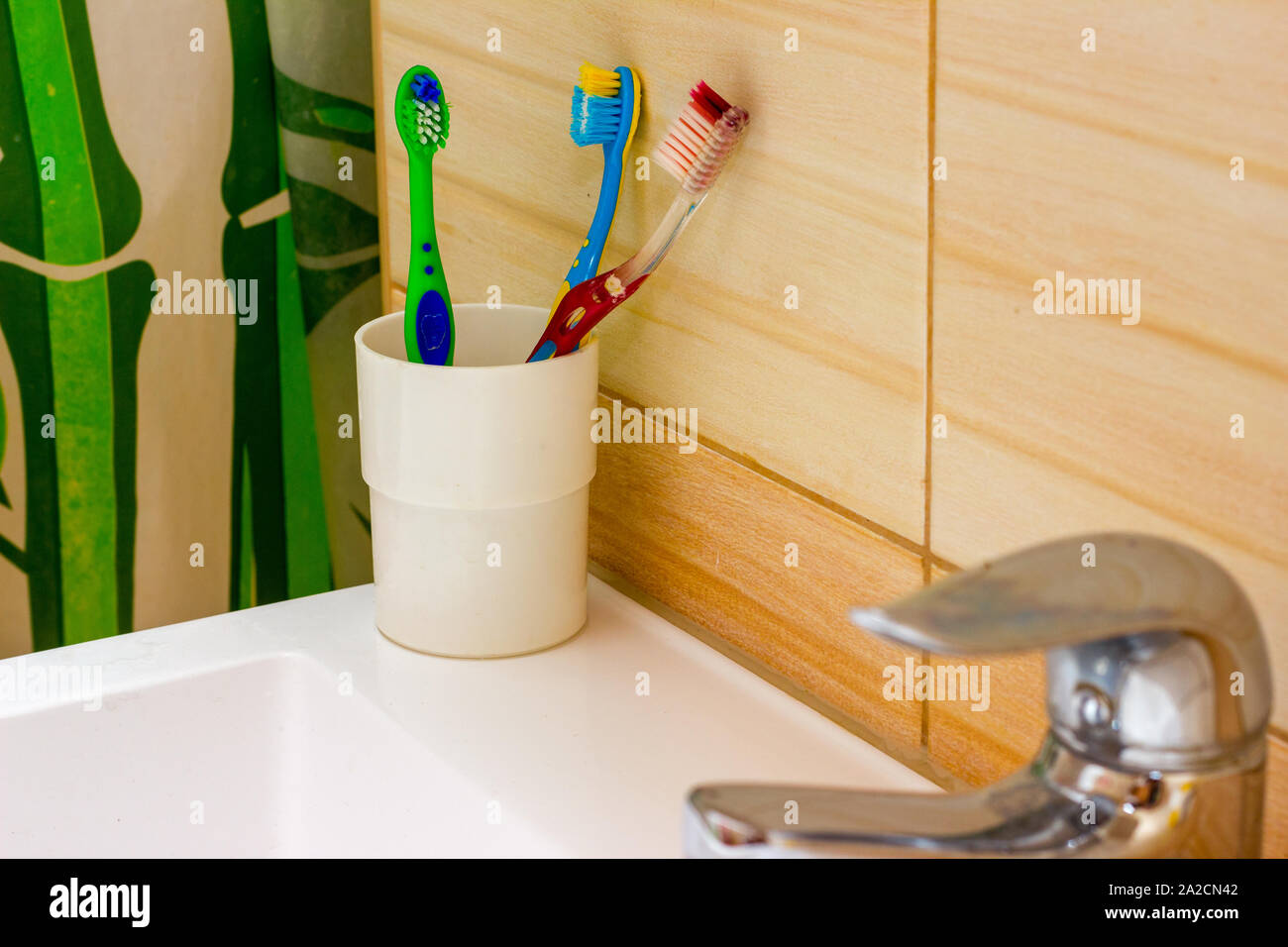 Toothbrushes stand on the sink on bathroom wall Stock Photo - Alamy