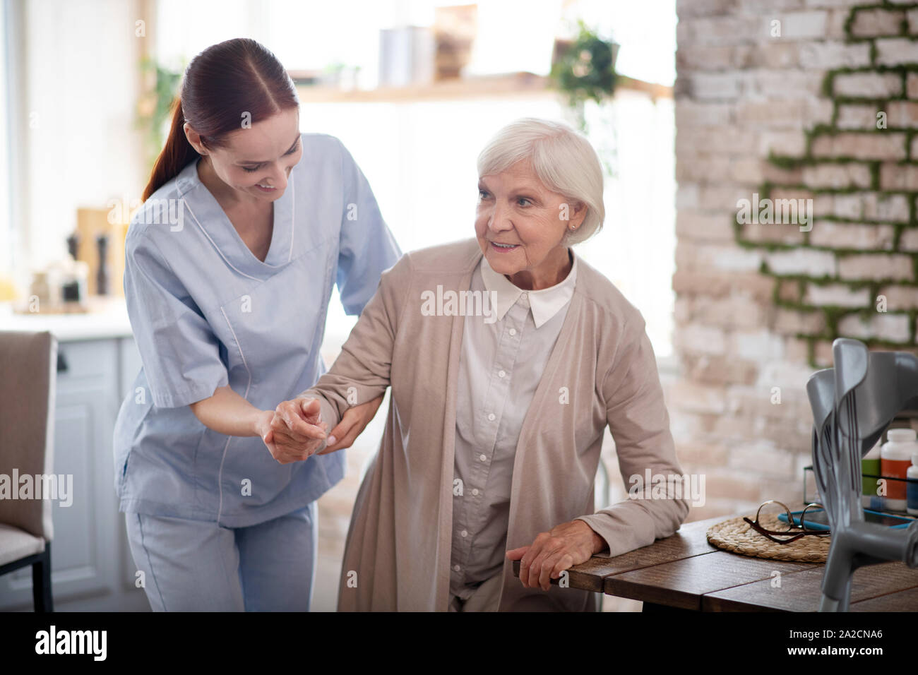 Caregiver smiling while helping aged woman to walk Stock Photo - Alamy