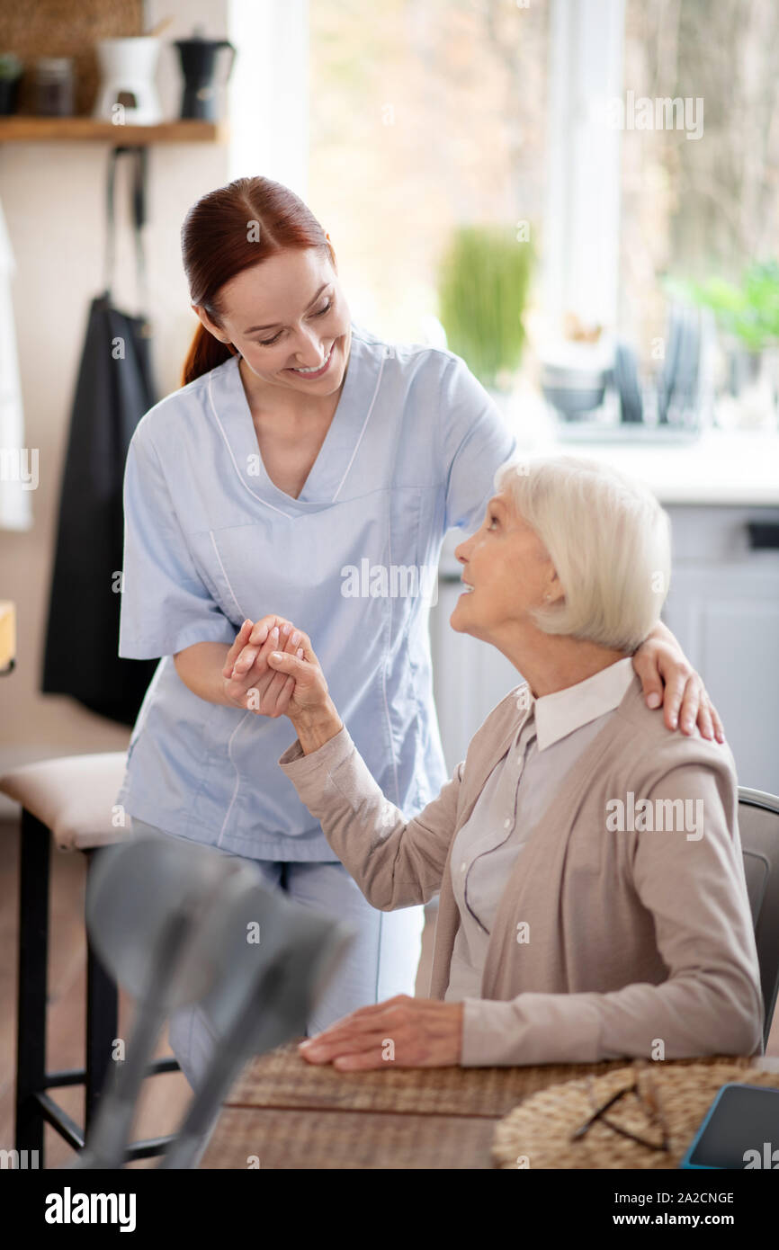 Smiling caregiver supporting pensioner after surgery Stock Photo - Alamy