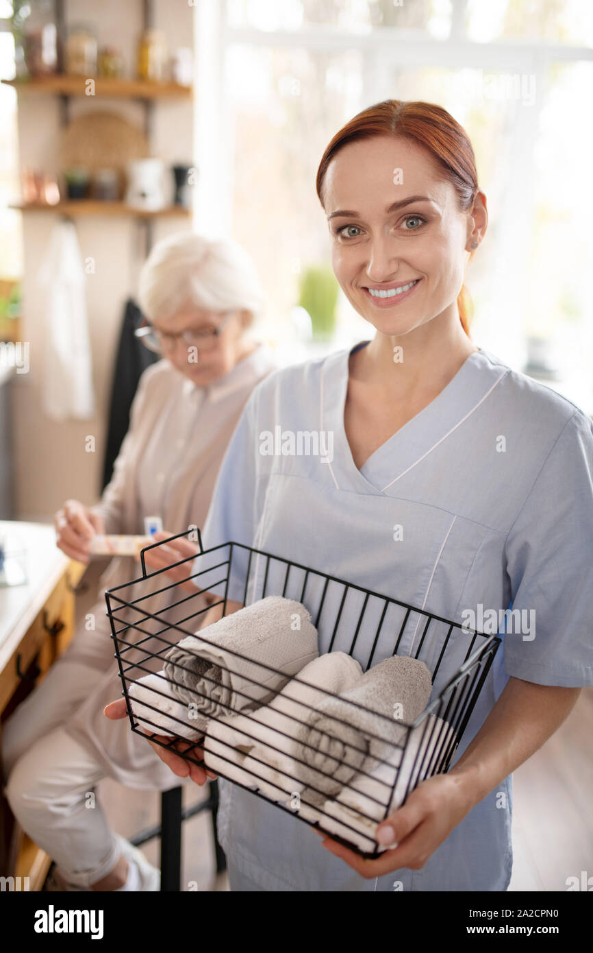 Personal caregiver smiling after washing towels Stock Photo - Alamy