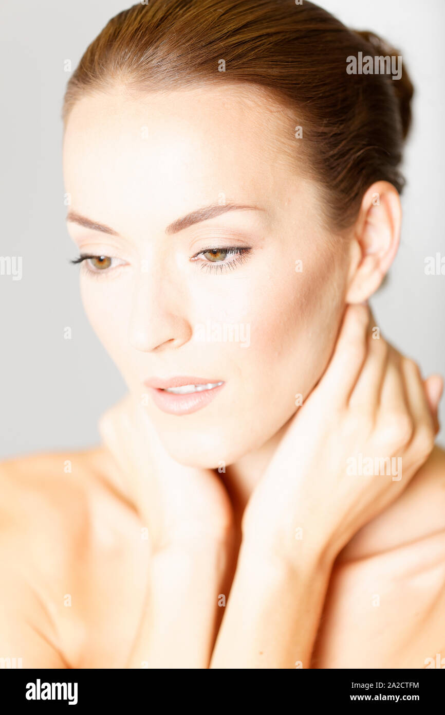 Beautiful young womans face with her hand resting on her chin and neck ...