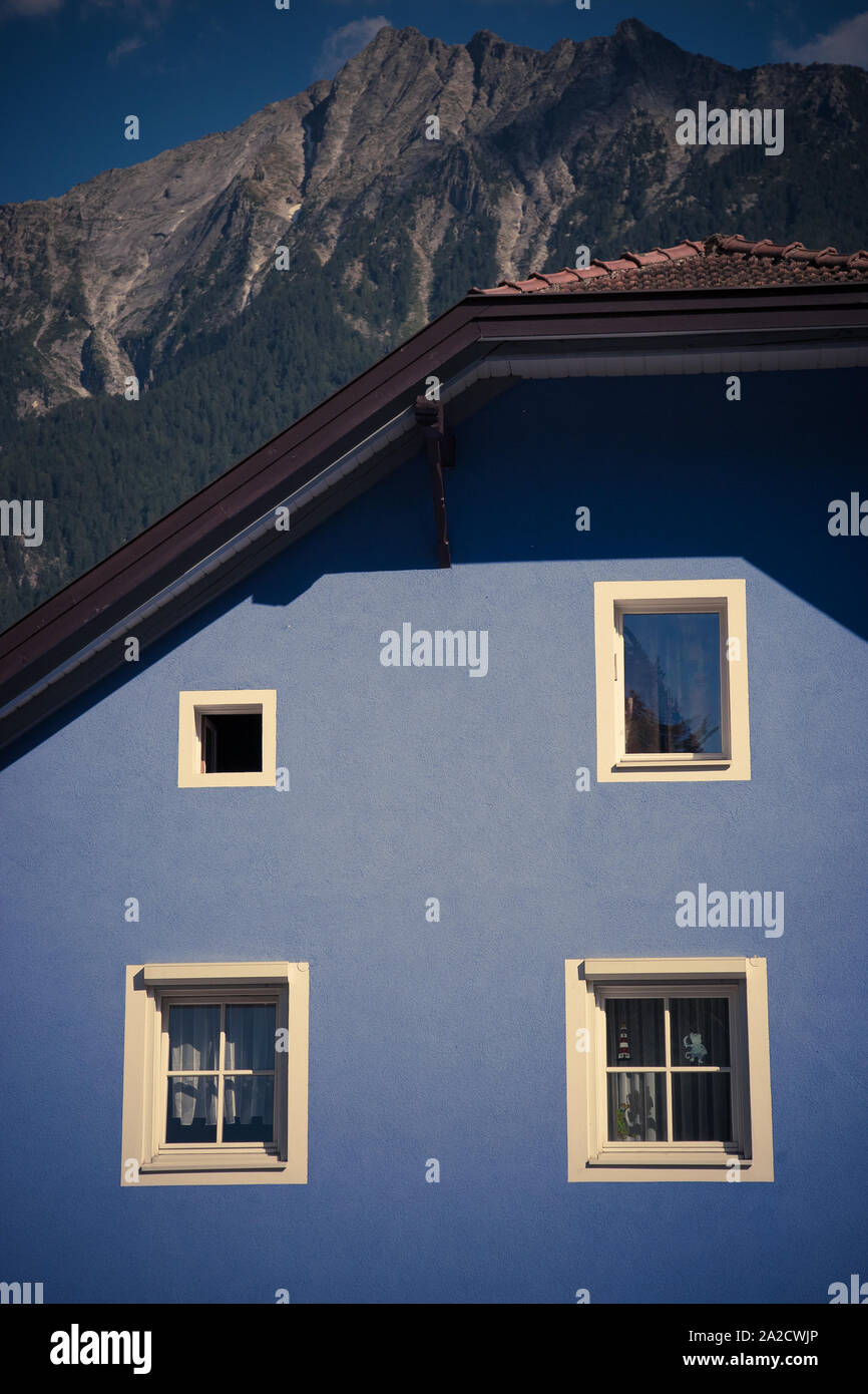 Blue house with white windows under Alps Stock Photo - Alamy