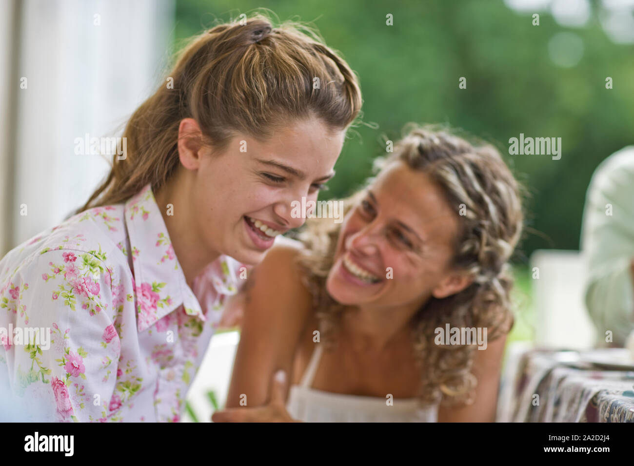 Happy teenage girl laughing with her mid-adult mother while at the ...