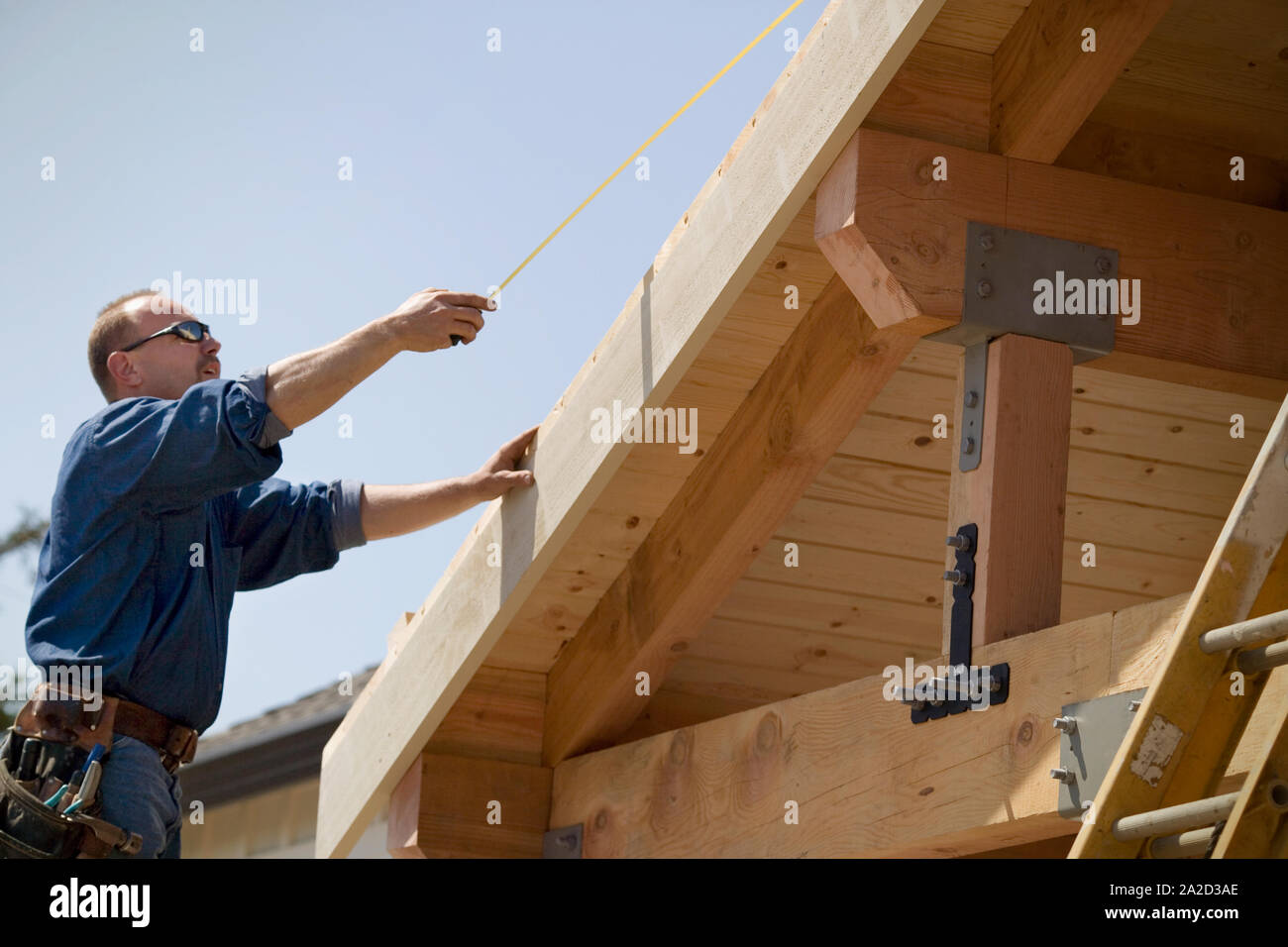 Male builder holding a tape measure on a house under construction Stock ...