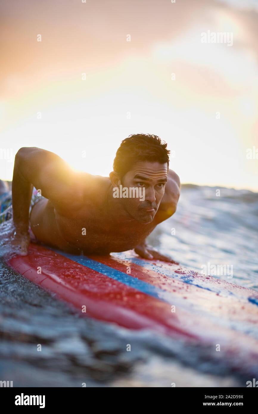 Male surfer prepares to push up into a standing position as a wave ...