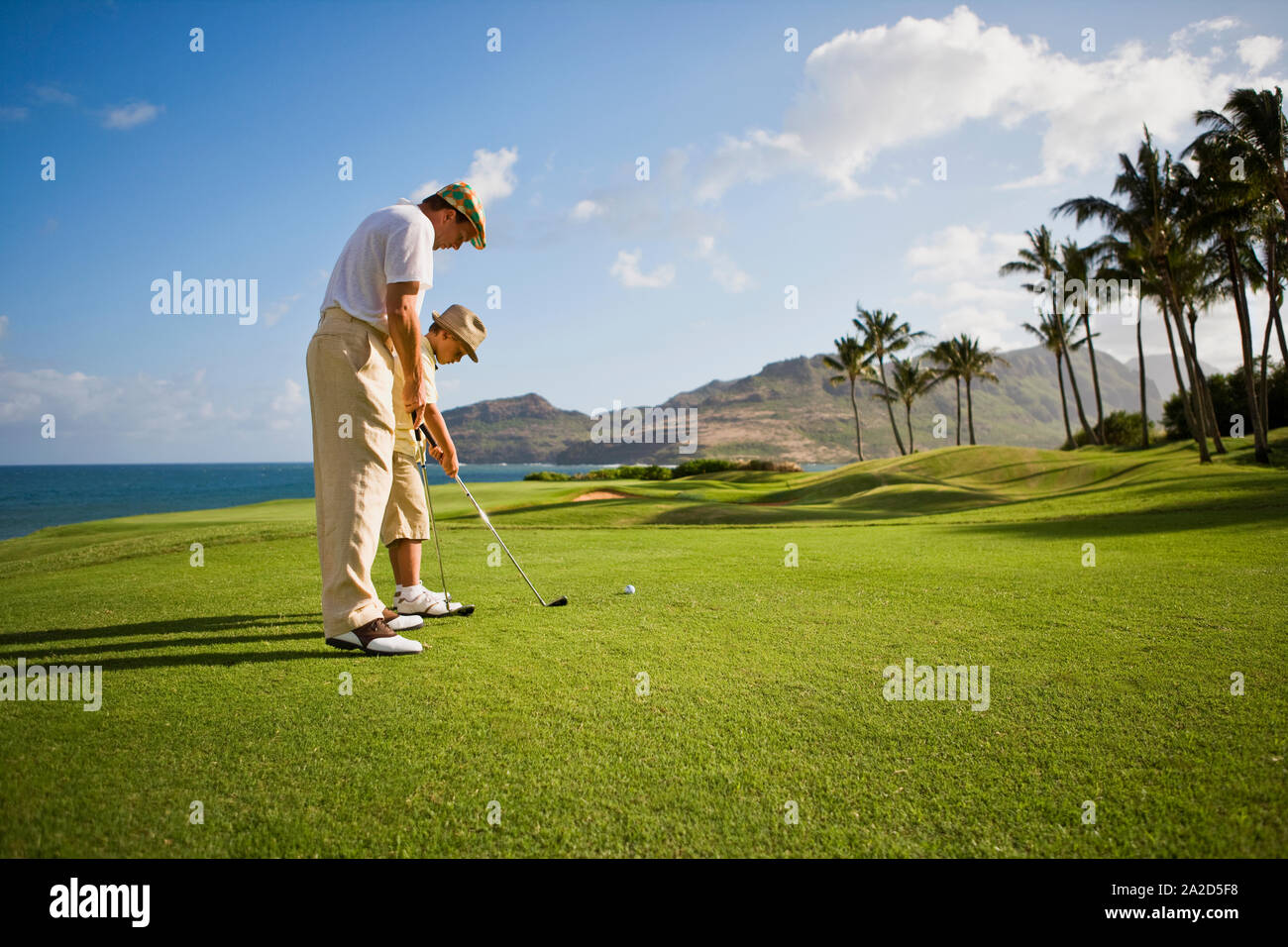 Male golfer helps his young son to play golf Stock Photo - Alamy